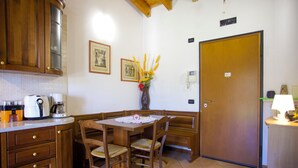 Uma cozinha com armários de madeira, uma mesa de jantar com cadeiras, uma cafeteira e um vaso com flores.