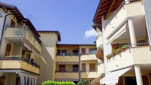 Um edifício com várias andares, varandas, toldos e céu claro.