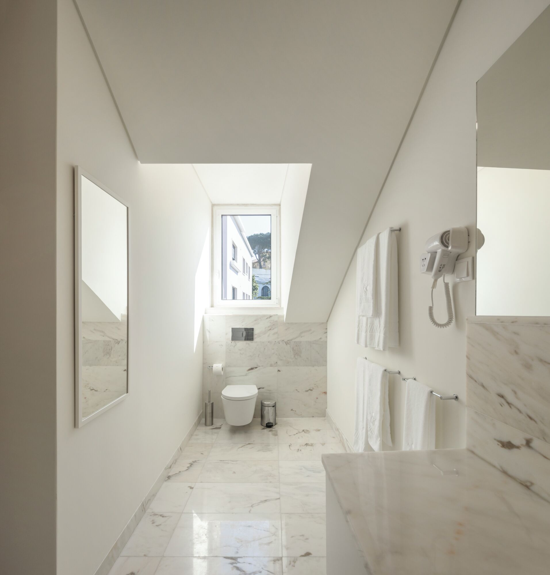Casa de banho moderna com claraboia, sanita, lavatório e secador de cabelo.