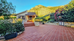 Uma casa com fachada de pedra, telhado em telhas e entrada frontal com degraus.