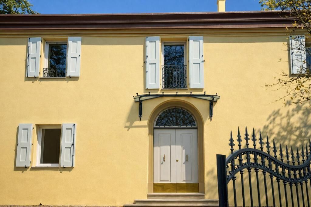Um edifício com fachada amarela, portas brancas e persianas.