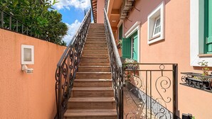 Escadaria que leva a um edifício com portão de metal e uma pequena janela.