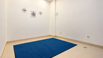 Quarto com carpete azul, paredes brancas e obras de arte com caligrafia árabe.