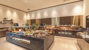 Uma área de buffet com diversas estações de serviço, um balcão de mármore e variedade de alimentos.