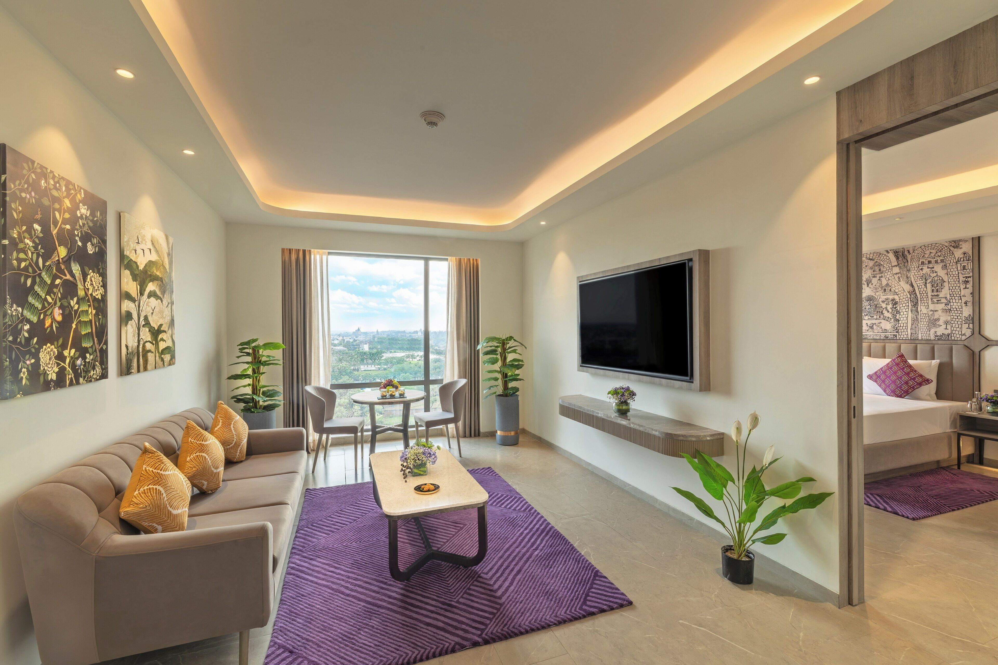 Uma sala de estar moderna com sofá, mesa de centro, televisão e plantas.