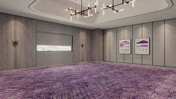Uma sala de conferências com uma janela grande, um tapete roxo e duas obras de arte emolduradas na parede.