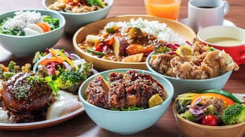 Diversos pratos, incluindo arroz, legumes e carne, servidos sobre uma mesa de madeira.