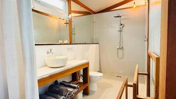 Uma casa de banho moderna com um espelho grande, uma sanita branca, um lavatório e um chuveiro.