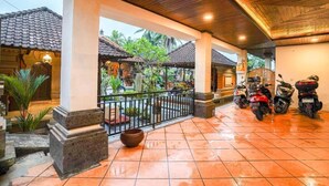 Uma área externa coberta com piso de azulejo, teto de madeira e corrimão.