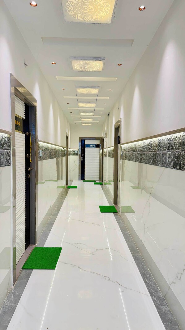 Um corredor com piso de mármore, iluminação embutida e azulejos de parede estampados.