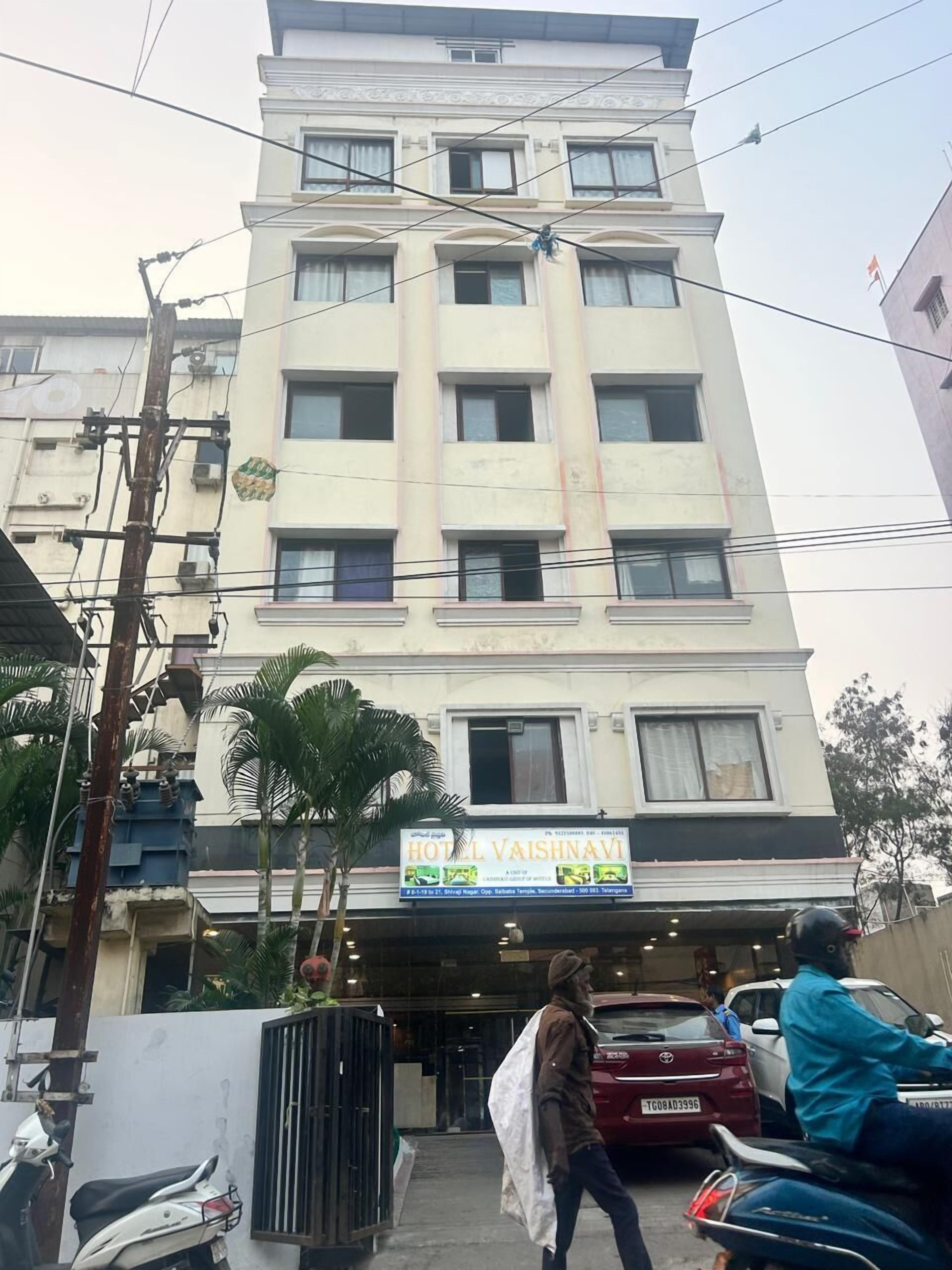 Um hotel com vários andares e uma placa indicando Hotel Vaishnavi.