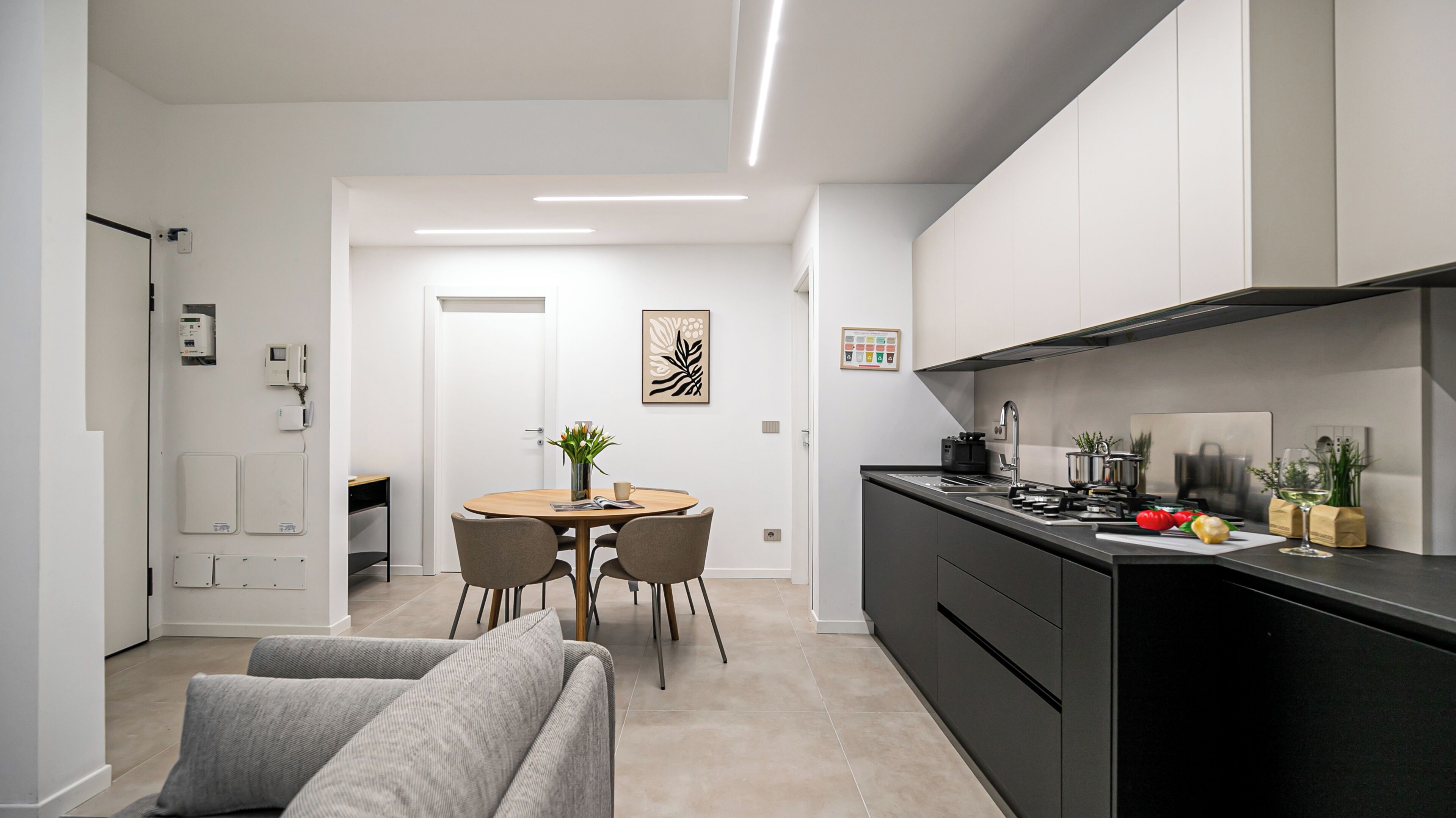 Uma cozinha moderna com bancada preta, eletrodomésticos de aço inoxidável e uma área de refeições com mesa redonda e cadeiras.