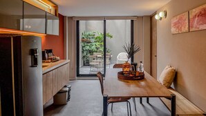 Cozinha moderna com frigorífico embutido, mesa de jantar de madeira e porta de correr de vidro que dá para área externa com mesa e cadeiras.