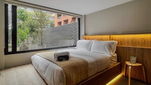 Quarto moderno com uma grande janela, cabeceira de madeira e mesa de cabeceira com uma moldura.