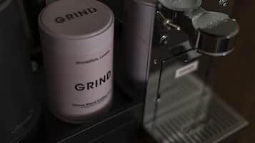 Máquina de café com recipiente rotulado 'GRIND' e suporte para cápsulas de café.
