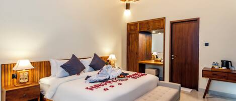 Quarto bem organizado com cabeceira de madeira, mesa de cabeceira com abajur, um banco e guarda-roupa de madeira.