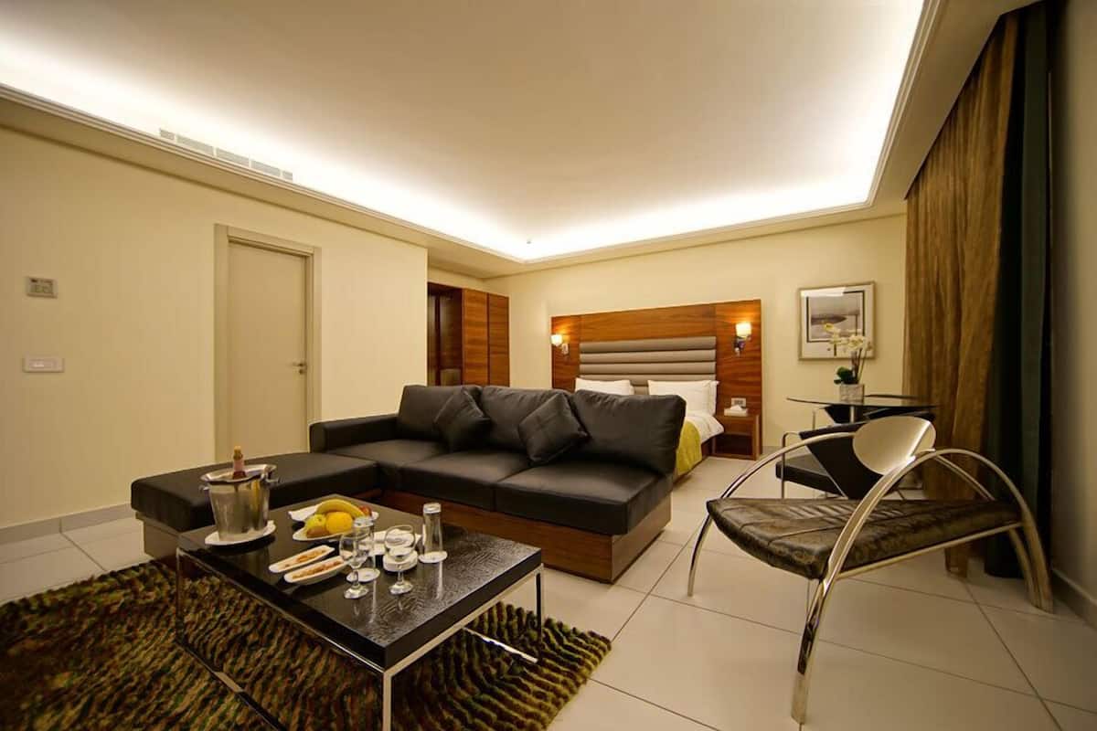 Uma sala de estar moderna com sofá, mesa de jantar, cadeira e cama com cabeceira de madeira.