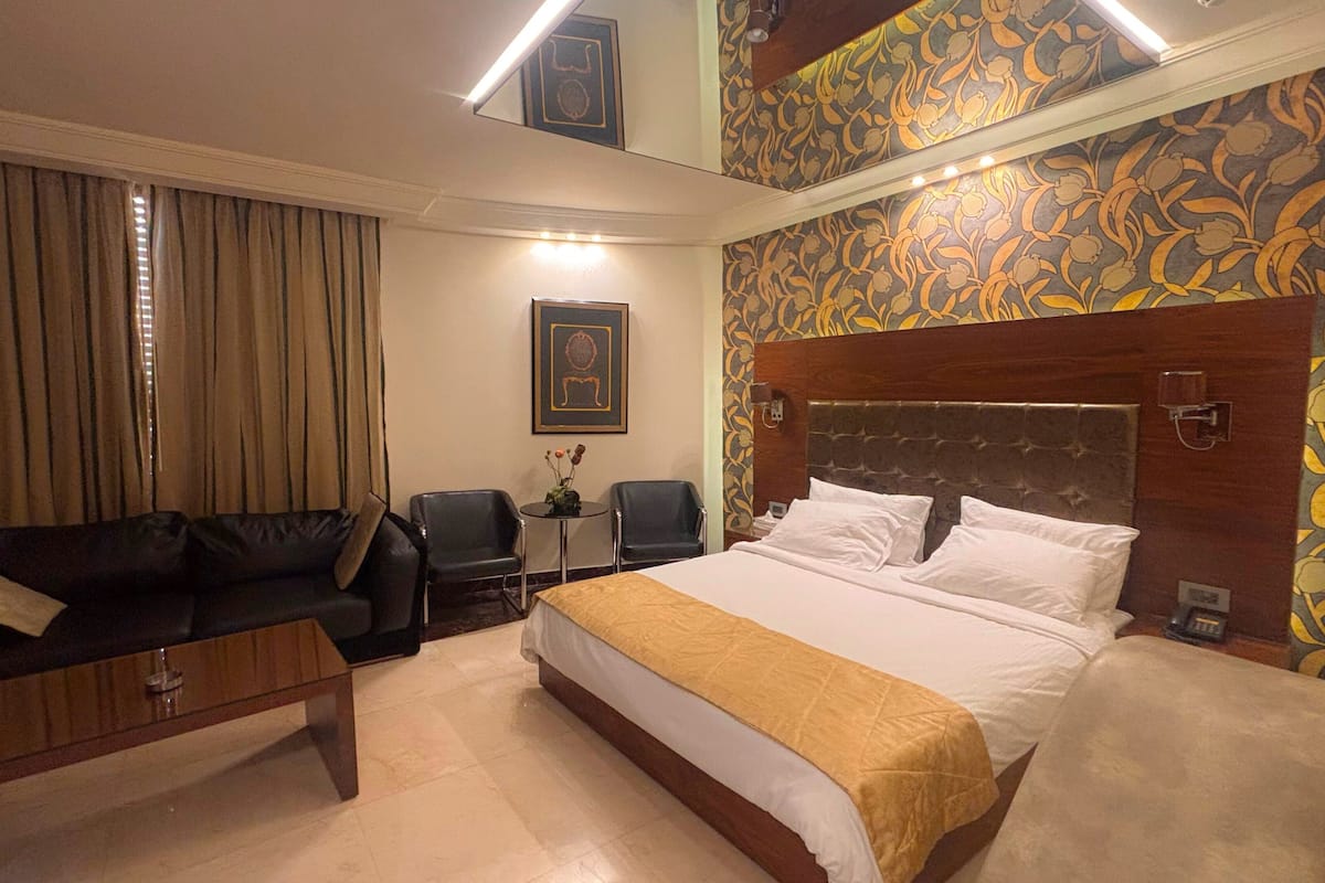 Quarto de hotel com cama, um sofá, uma mesinha com um vaso e uma cadeira.
