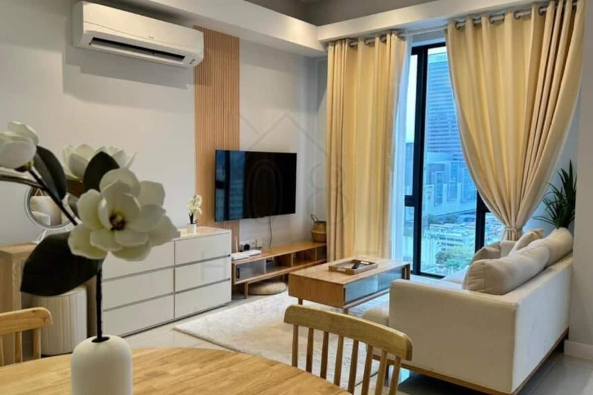 Uma sala de estar moderna com um sofá, uma televisão e uma área de jantar com mesa e cadeiras.