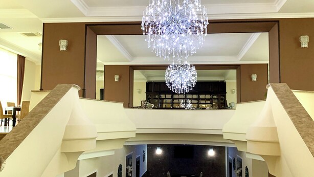 Um amplo hall de entrada com um lustre imponente, escadaria e área de estar.