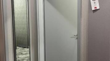 Um corredor com porta fechada, espelho e gancho para casacos com etiqueta.