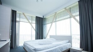 Quarto de hotel com cama, escrivaninha e janela com cortinas.