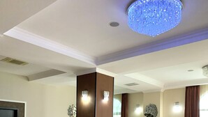 Um hall amplo com um candelabro, poltronas de couro, um sofá e uma porta com o número 5.