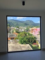 Quarto com uma grande porta de vidro deslizante que dá para uma varanda com vista para uma cidade e montanhas.