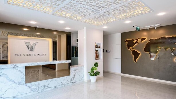 Uma área de recepção com balcão de mármore, um mural de mapa-múndi e um design de teto moderno.