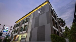 Um hotel moderno em vários andares, com um logotipo em destaque na fachada e uma entrada bem iluminada.