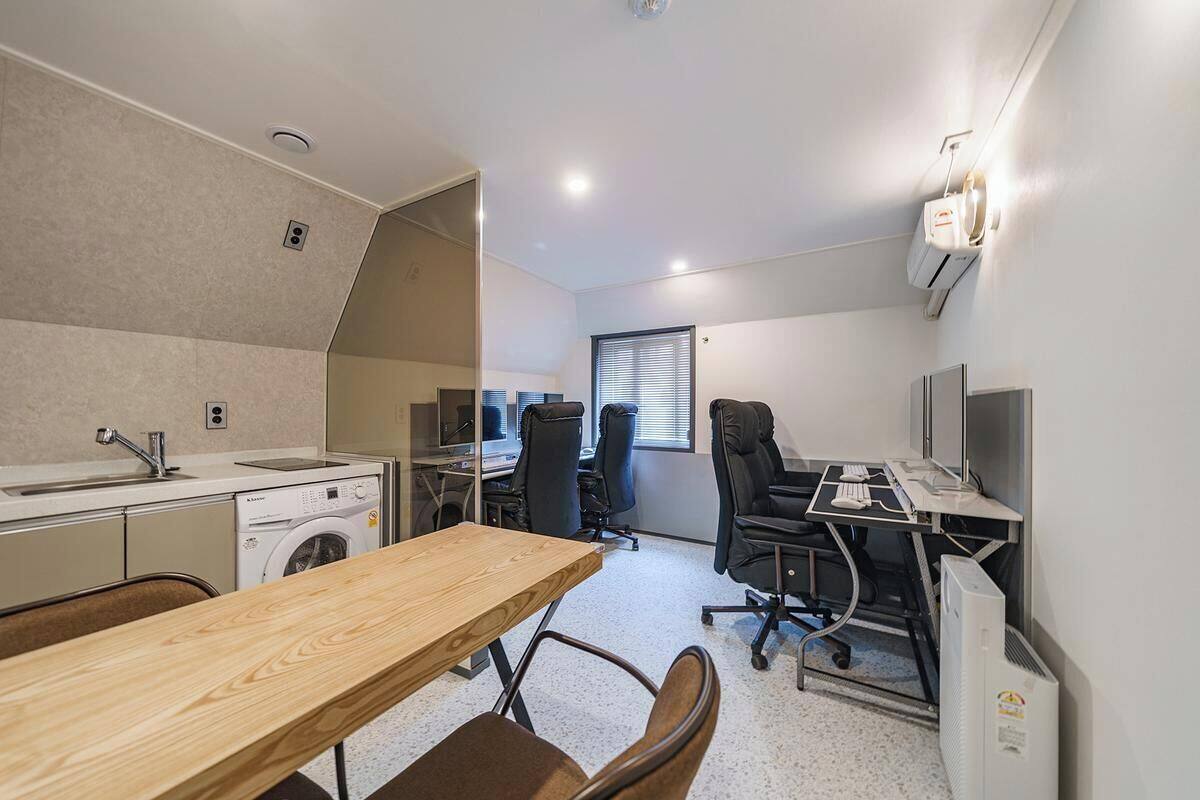 Cozinha compacta com pia, máquina de lavar e área de refeições com mesa e cadeiras de madeira.