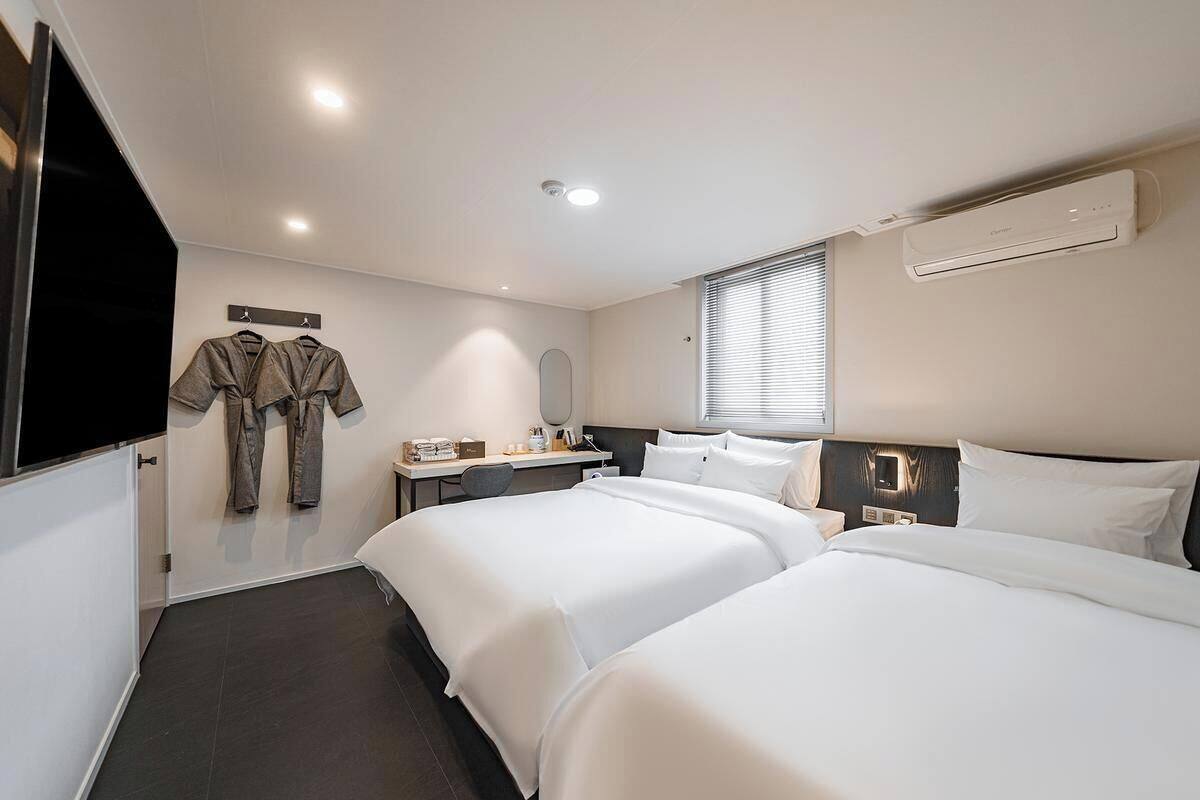 Quarto de hotel com duas camas, uma escrivaninha, televisão e porta-robes.