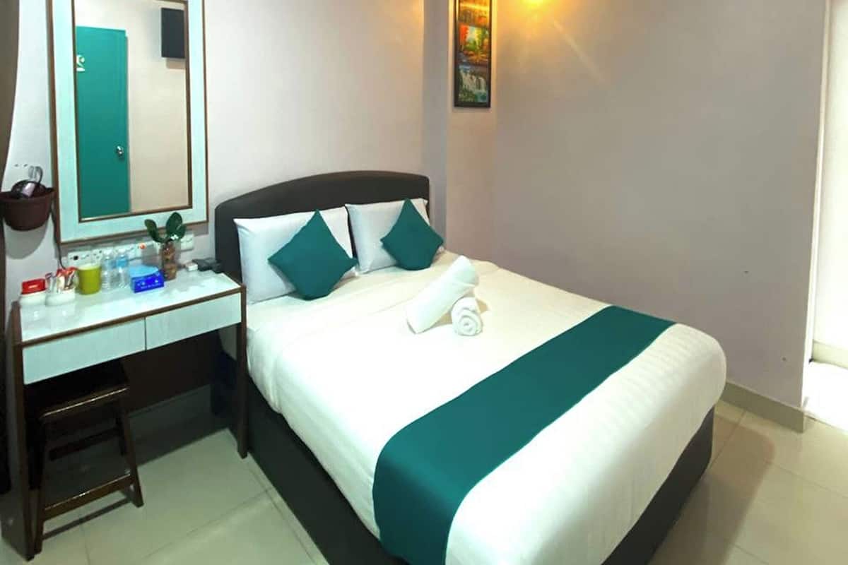 Quarto de hotel com cama, mesa de cabeceira, espelho e ar condicionado.