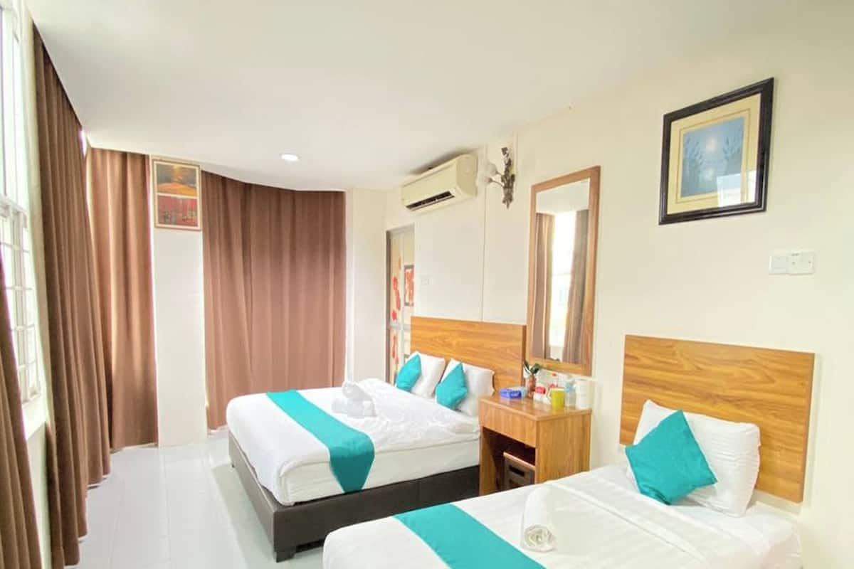 Quarto de hotel com duas camas, uma escrivaninha, um espelho e uma janela com cortinas.