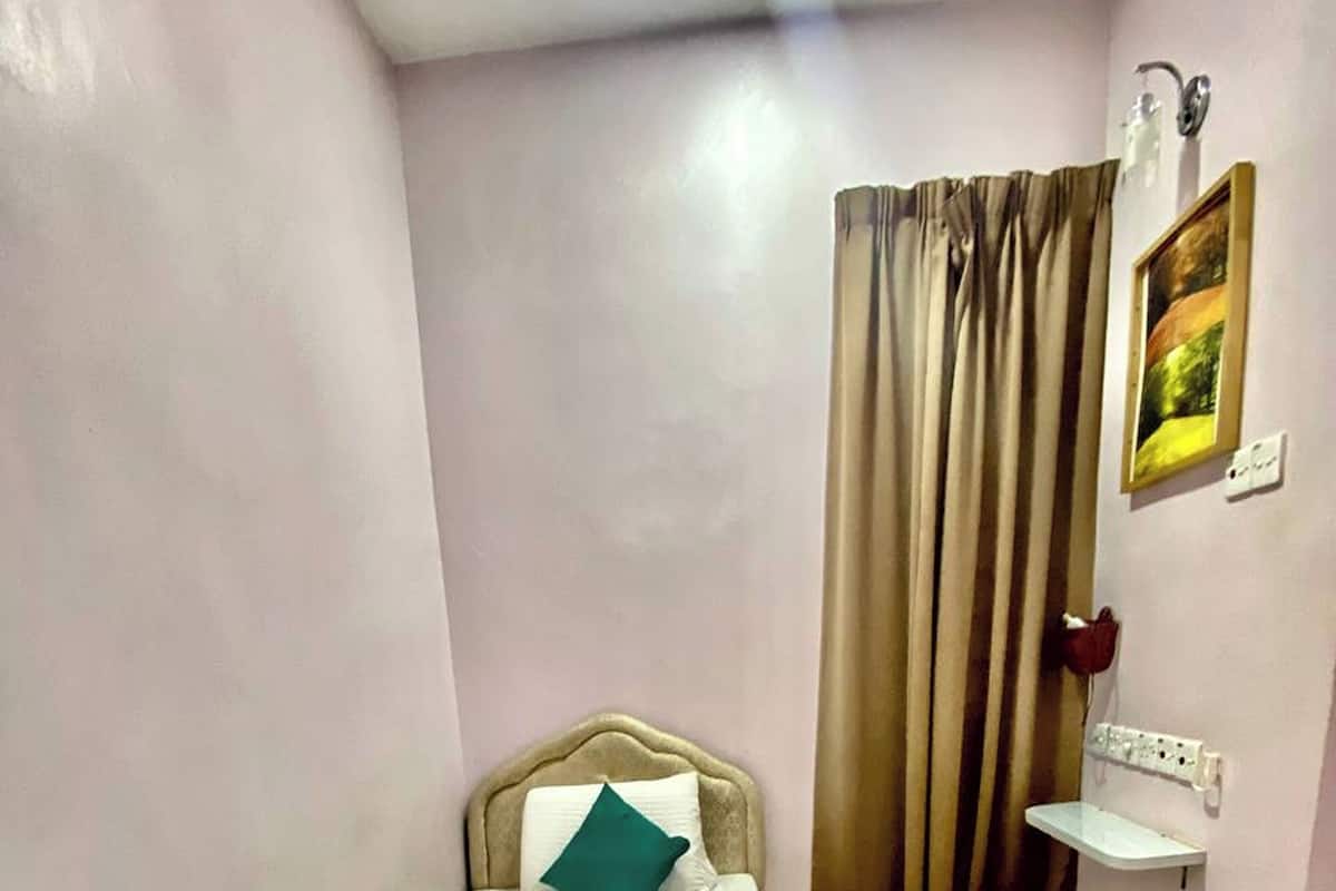 Quarto com cama, mesa de cabeceira, prateleira na parede, cortina e um quadro.