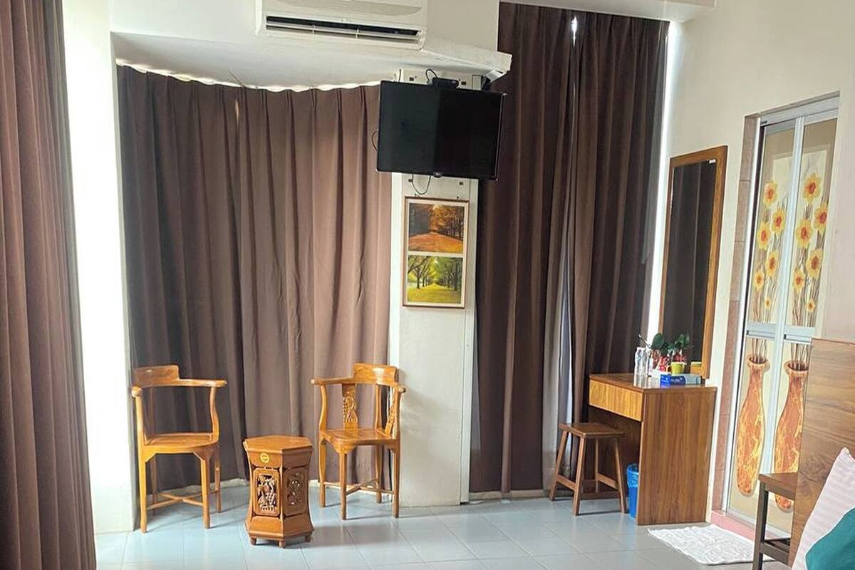 Quarto de hotel com uma cama, uma mesa, duas cadeiras e uma televisão.