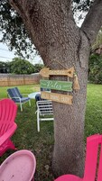 Uma árvore com uma placa de madeira que diz: "Regras do Jardim: Relaxe, Descontraia, Aproveite".