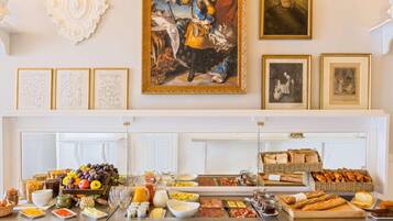 Buffet com diversos tipos de comida, obra de arte na parede e um armário branco.