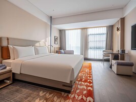 Quarto de hotel moderno com uma cama grande, uma escrivaninha e uma cadeira.