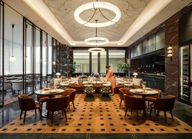 Um restaurante moderno com área de estar central, bar e vista para a cozinha.