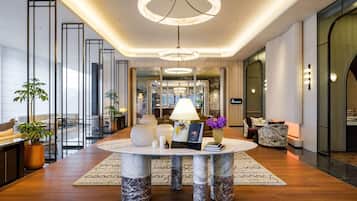 Um lobby moderno de hotel com uma mesa de mármore, assentos e vista para a cidade.