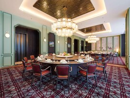 Sala de conferências com uma mesa redonda, várias cadeiras e um candelabro.