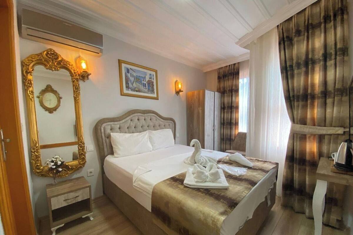 Quarto de hotel com uma cama grande, mesa de cabeceira, espelho e um quadro na parede.