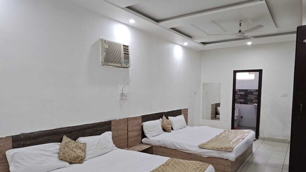 Quarto de hotel com duas camas, um ventilador de teto e janela com vista.