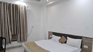 Quarto com cama, mesa de cabeceira, cadeira e janela com cortinas.