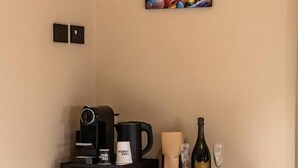 Uma cozinha compacta equipada com cafeteira, mini-geladeira e uma garrafa de vinho.