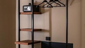 Estante de madeira em vários níveis com suportes de metal preto, exibindo um rádio e roupas penduradas.