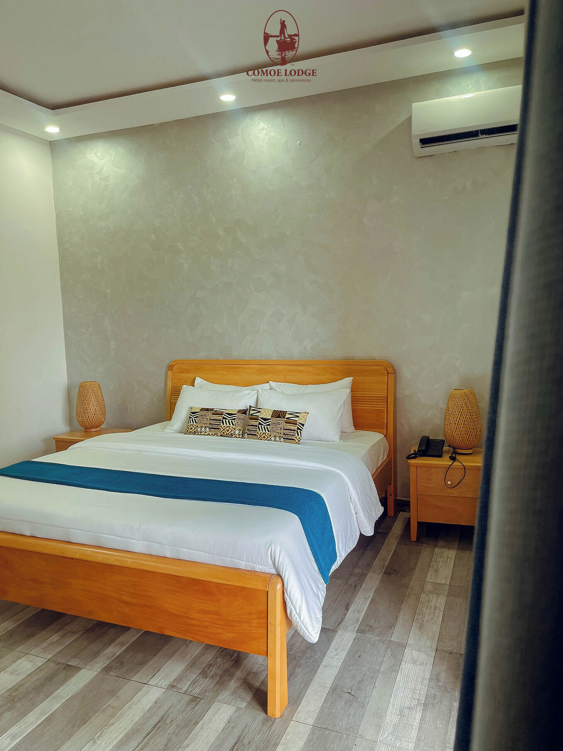 Quarto de hotel com uma cama, abajures, telefone e aparelho de ar condicionado.