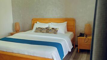 Quarto de hotel com uma cama, abajures, telefone e aparelho de ar condicionado.