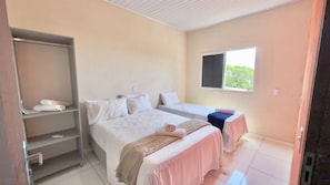 Quarto com uma cama, duas mesas de cabeceira, um guarda-roupa e uma janela.